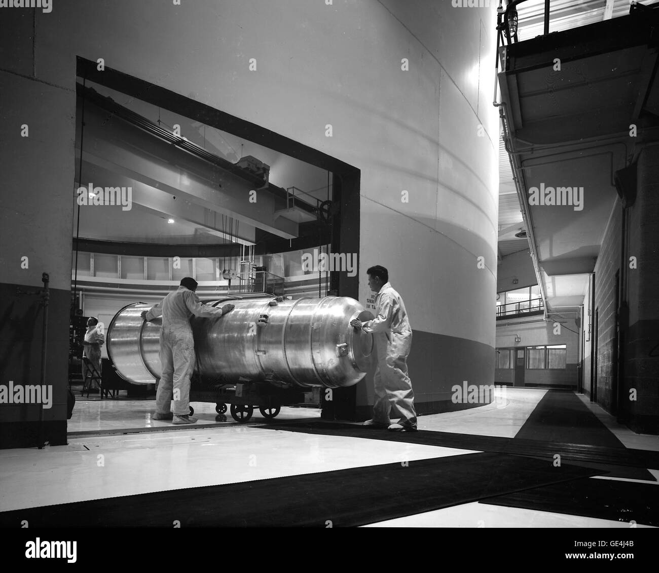 Technicians wheel a large "thimble" containing experiments for ...