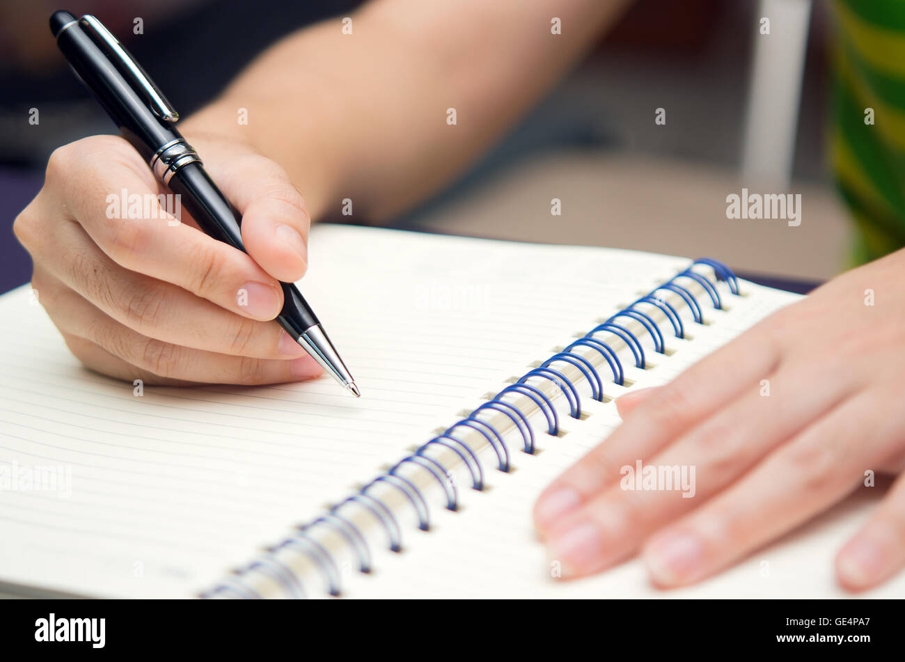 A girl hand is holding a pen and writing on a book Stock Photo - Alamy