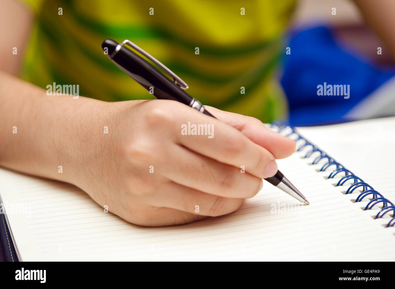 A girl hand is holding a pen and writing on a book Stock Photo - Alamy