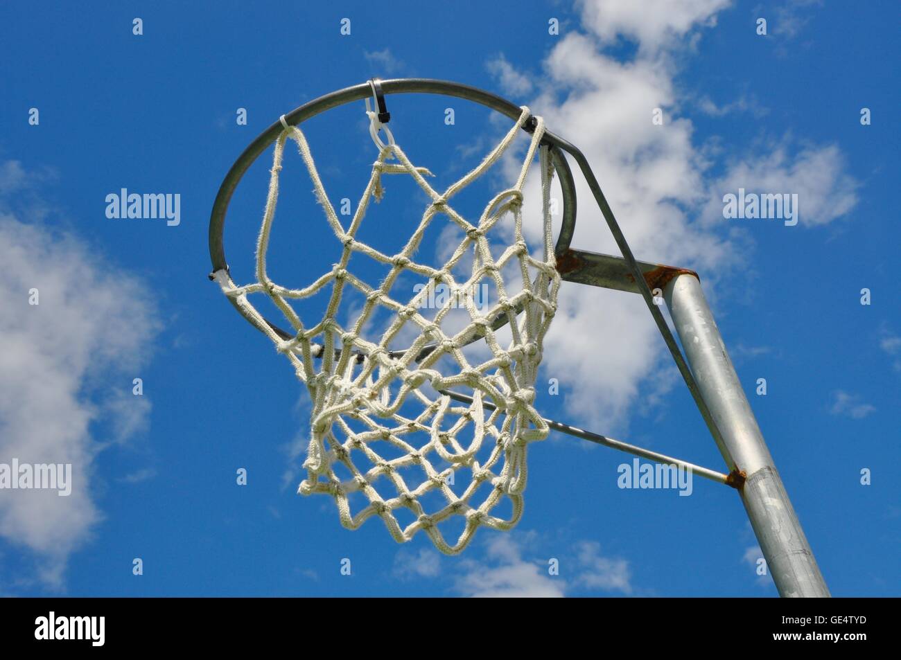 Abstract perspective of a netball rim with net against a blue sky and ...
