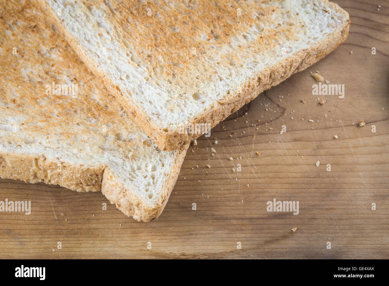 Close focus on edge of brown whole wheat toast on wood background with ...