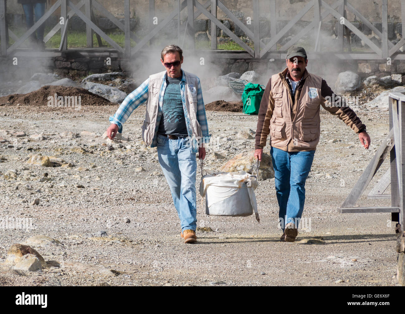 Man carrying a pan after cooking the food in the geothermal ground by ...