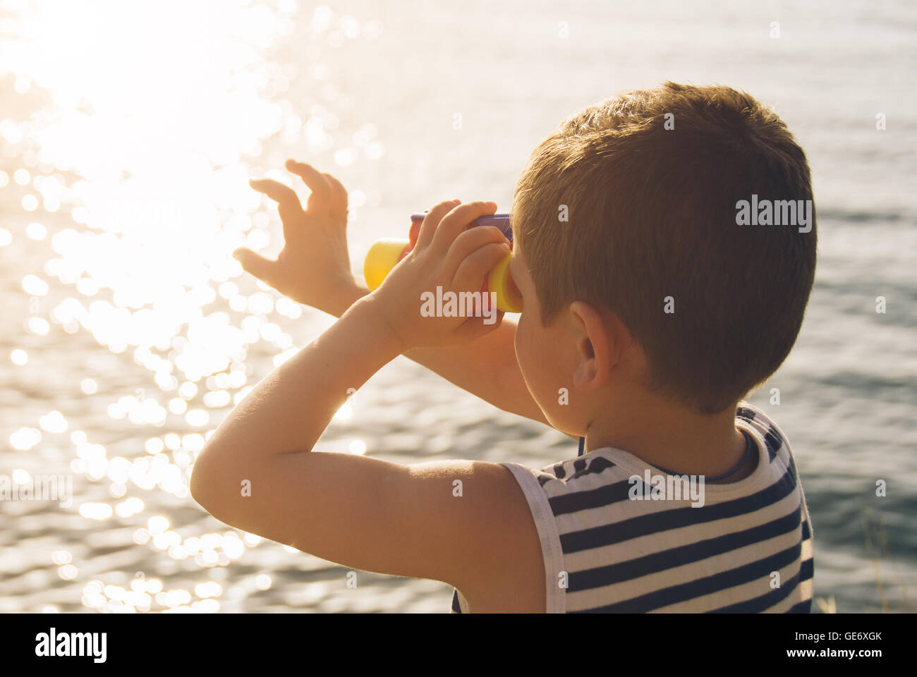 little boy looks into the distance through binoculars and touches his ...