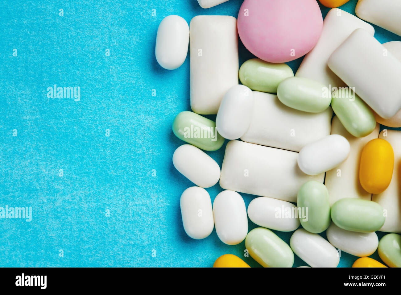 Different chewing gums, mint candies and drops on bright blue ...