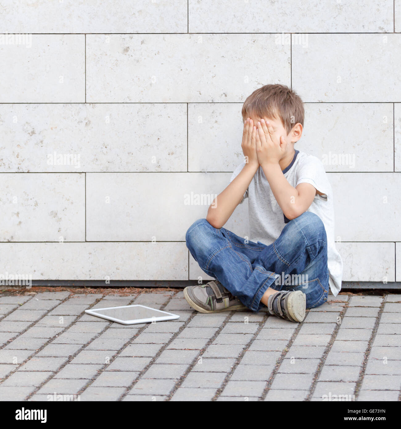 Little boy tired sad and stressed with tablet computer PC. Kid sitting ...