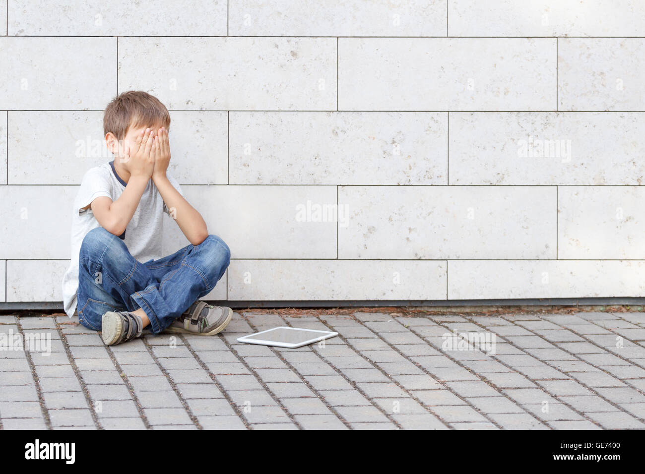 Little boy tired sad and stressed with tablet computer PC. Kid sitting ...