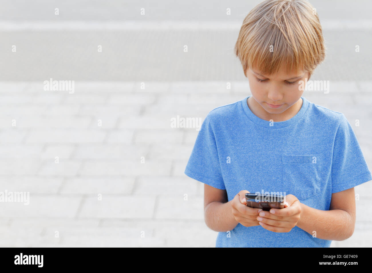 Boy with mobile phone in the street. Child looking at the screen ...