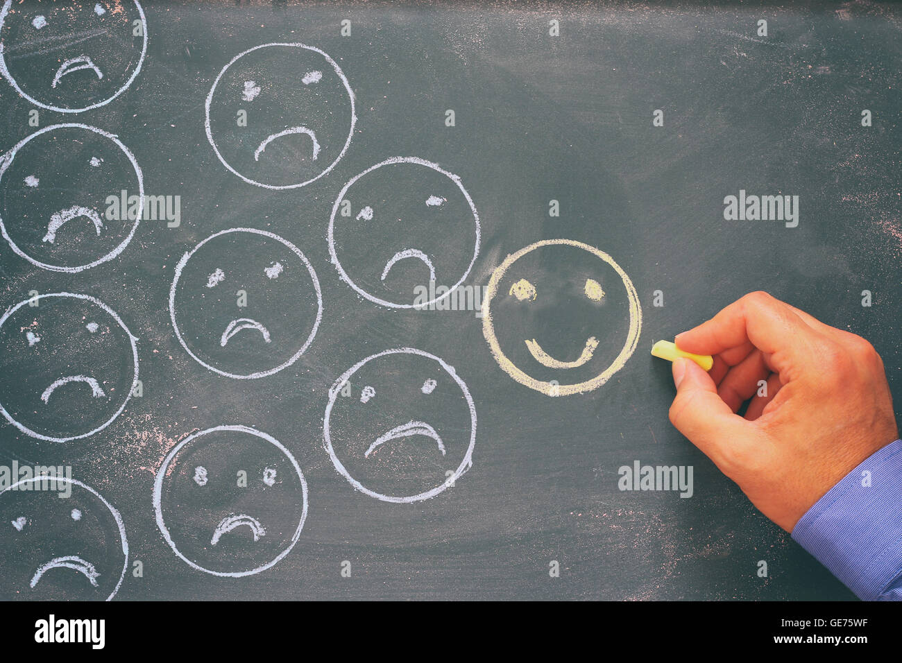 Leadership Concept image, male hand drawing smiley face over chalkboard ...