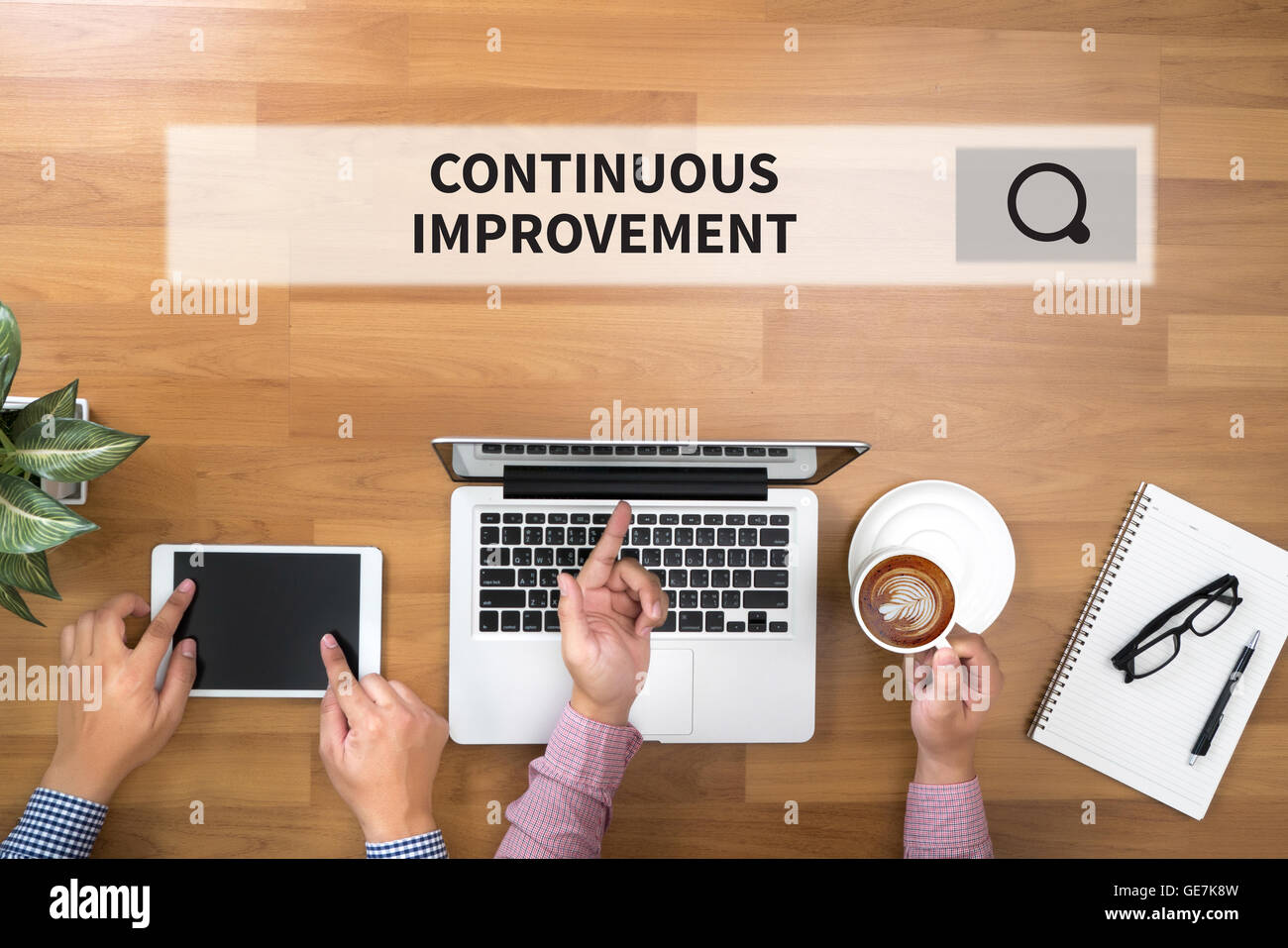 CONTINUOUS IMPROVEMENT Two Businessman working at office desk and using ...