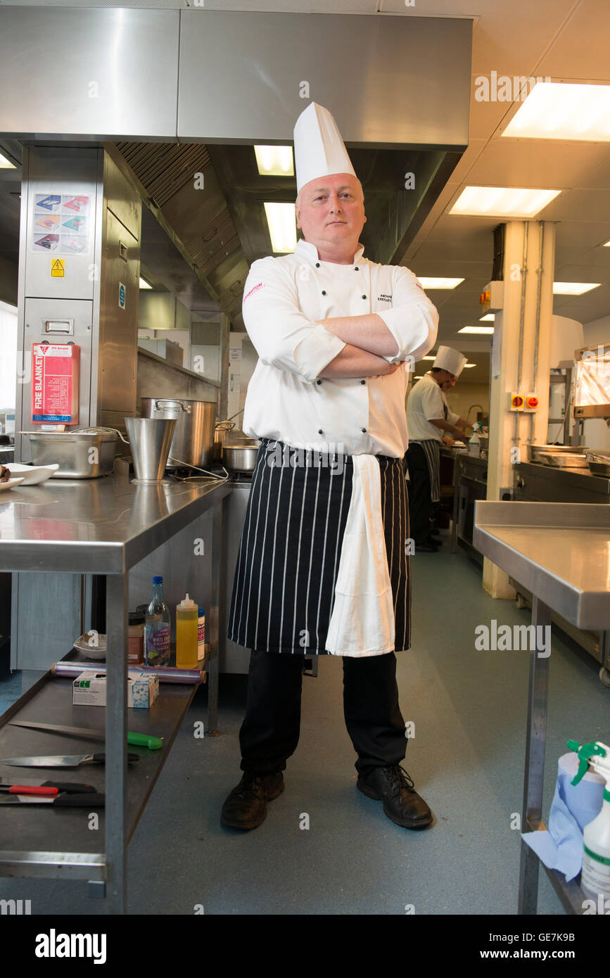 Head chef at Brighton Race course stands in his kitchen in typical chef ...