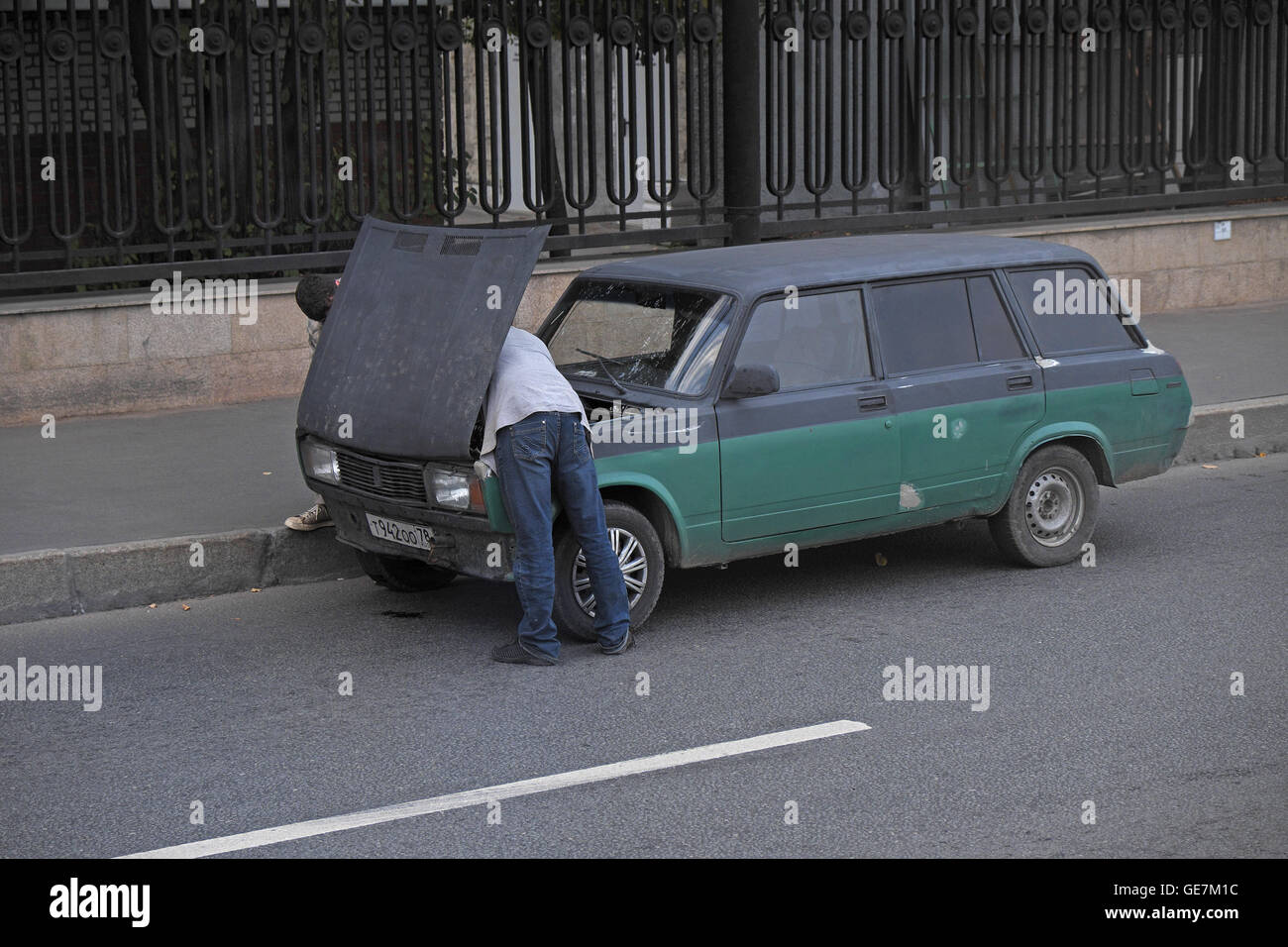 Two men trying to repair an old car at the roadside, St Petersburg ...