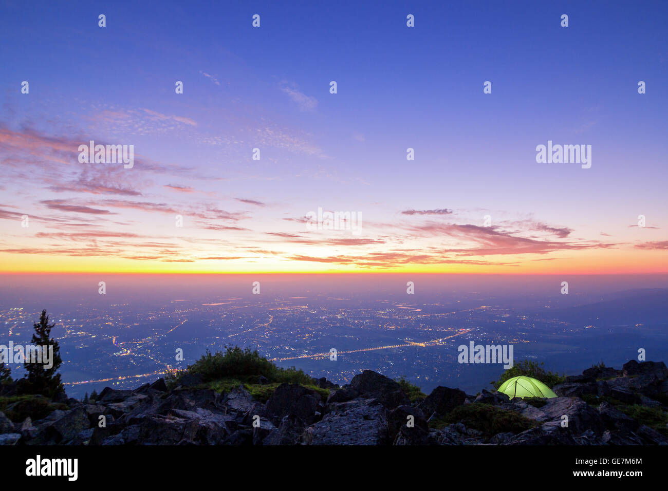 camping in the mountains and beautiful sunrise over the city in Europe ...