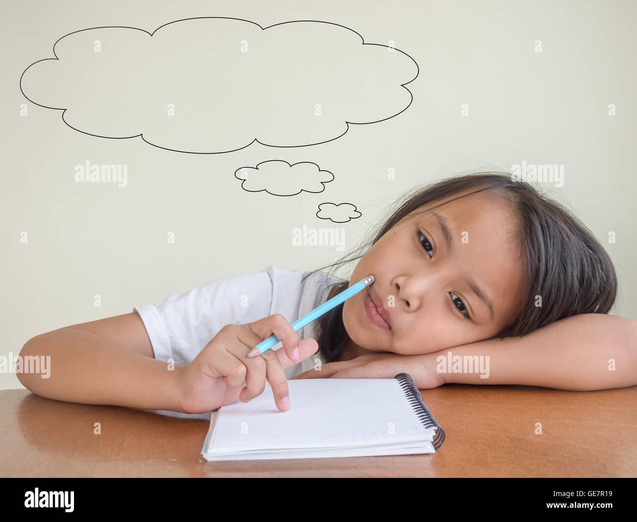 Little asian girl writing with pencil sitting on the wooden table Stock ...