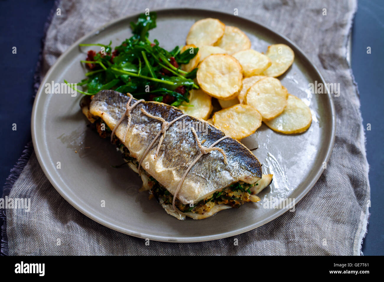 Stuffed sea bass with salad and potatoes Stock Photo - Alamy