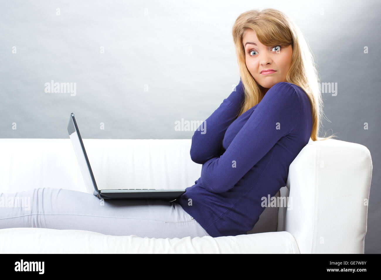 Surprised and scared woman sitting on sofa with laptop, computer ...