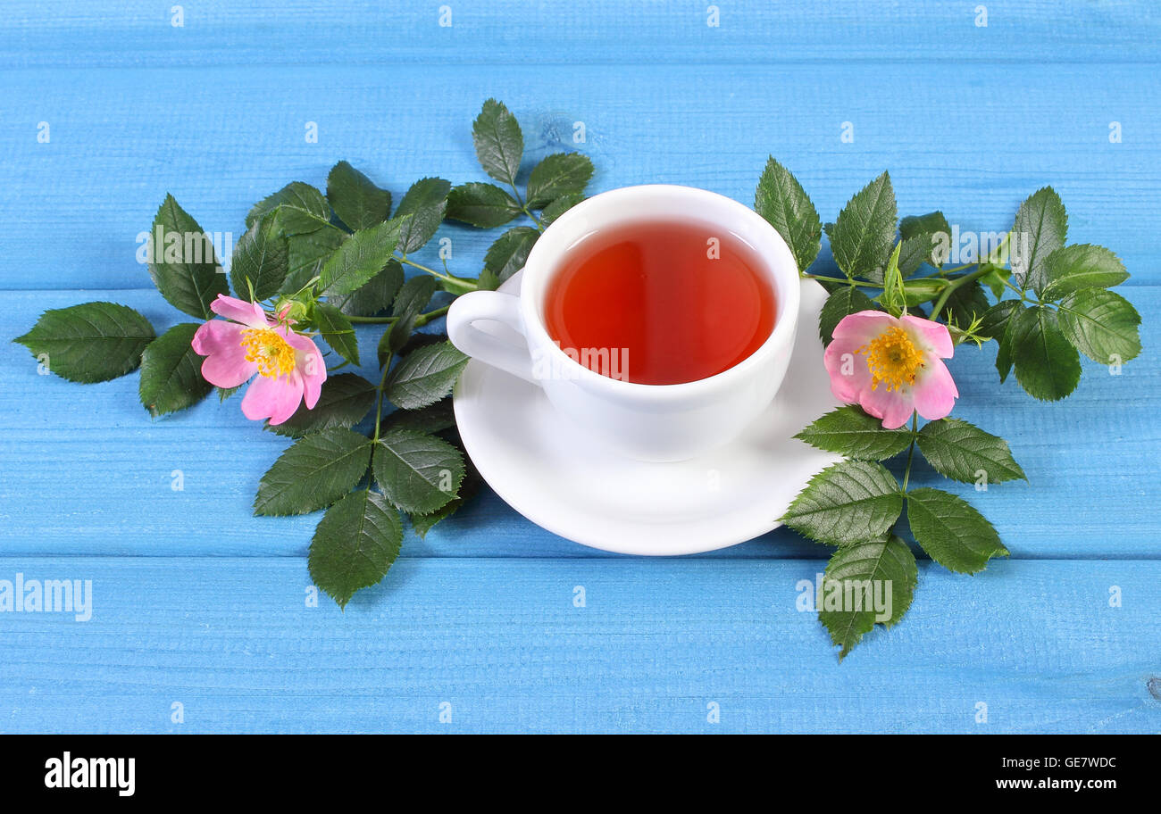 Cup of hot tea with wild rose and blooming flowers on blue boards Stock ...