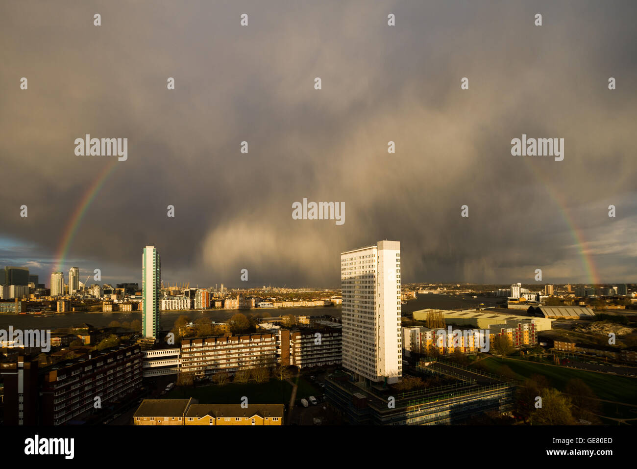 A massive colourful rainbow breaks during a rainstorm over high-rise ...