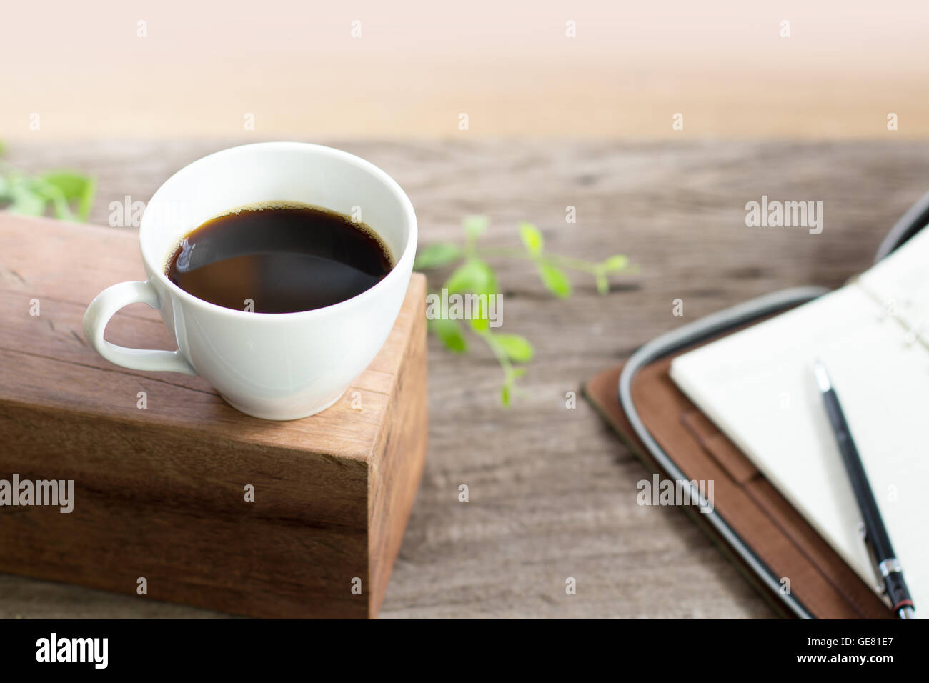 white cup coffee with note book on wooden top table isolated bright ...