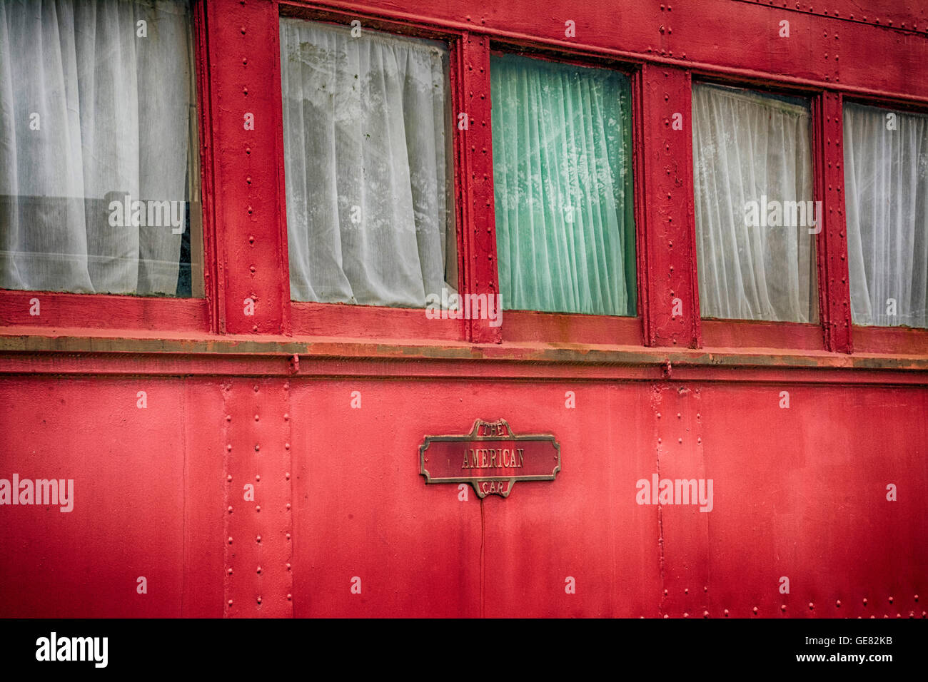 A weathered & Vintage red passenger train car with white curtains ...