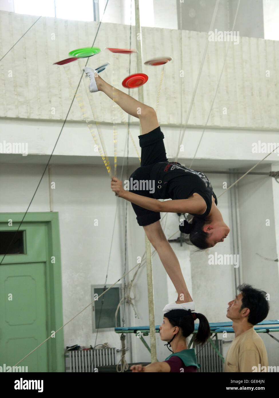Girl acrobat balancing on someone's head while spinning plates. Beijing ...