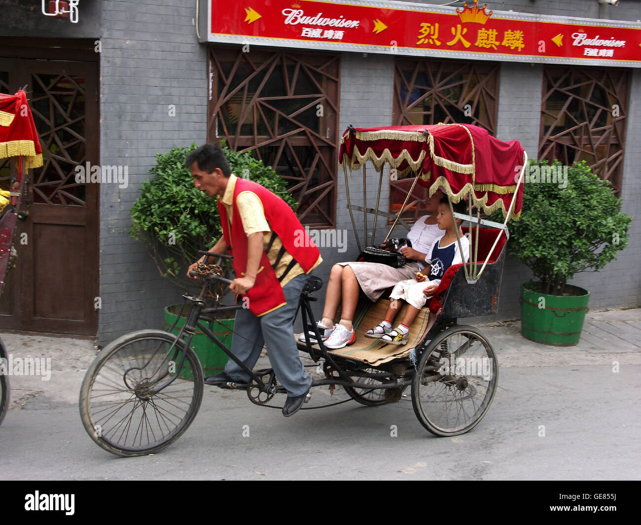 Bicycle rickshaw taking tourists through a hutong neighborhood. Beijing ...