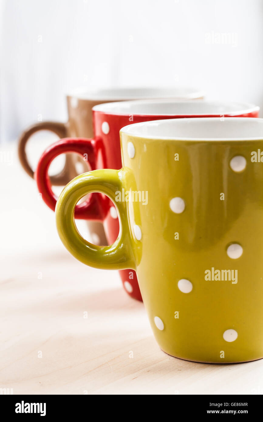 Three colored cups standing in a row Stock Photo - Alamy