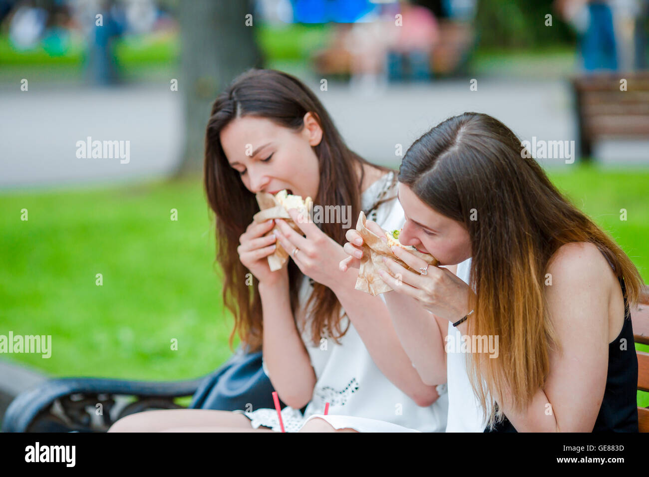 Caucasian women eats hamburger fast food sandwich on the street ...