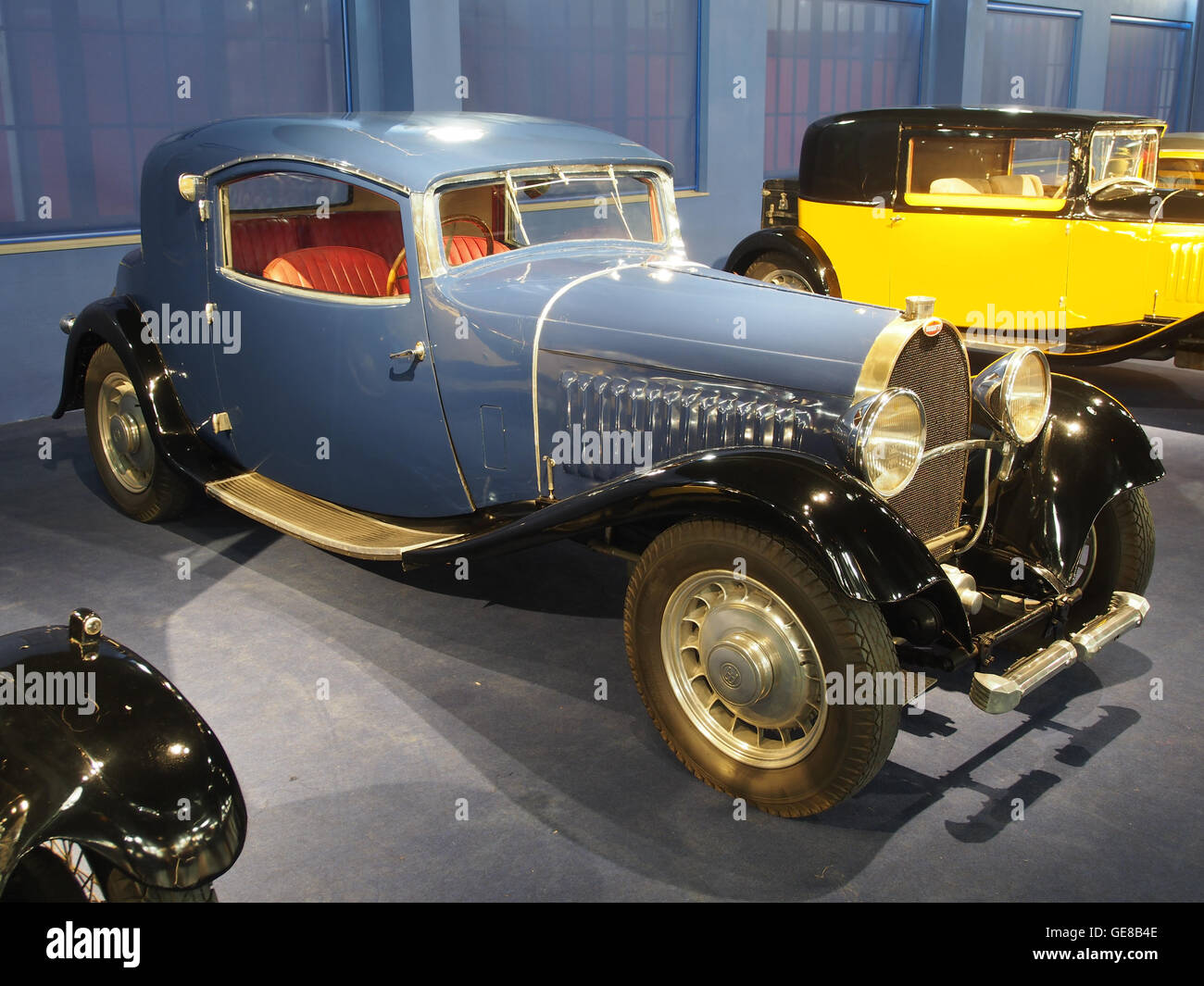 This image features a classic blue Bugatti with black fenders ...
