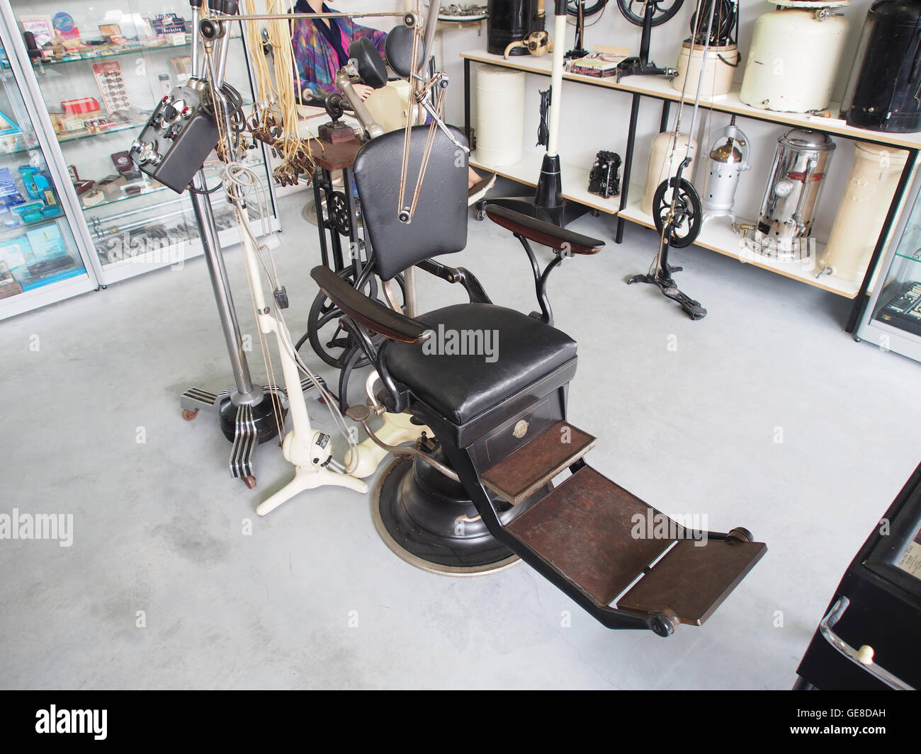 This image depicts an antique dentist's chair, with various tools such ...