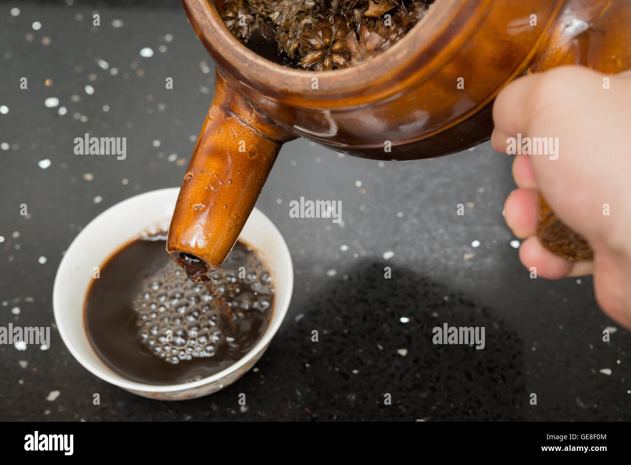 pouring herbal tea from an enamel pot with herb to a bowl Stock Photo ...