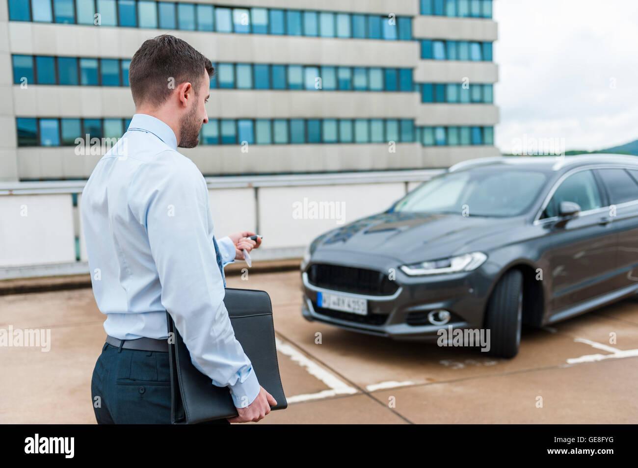 Businessman opening car on parking lot Stock Photo - Alamy