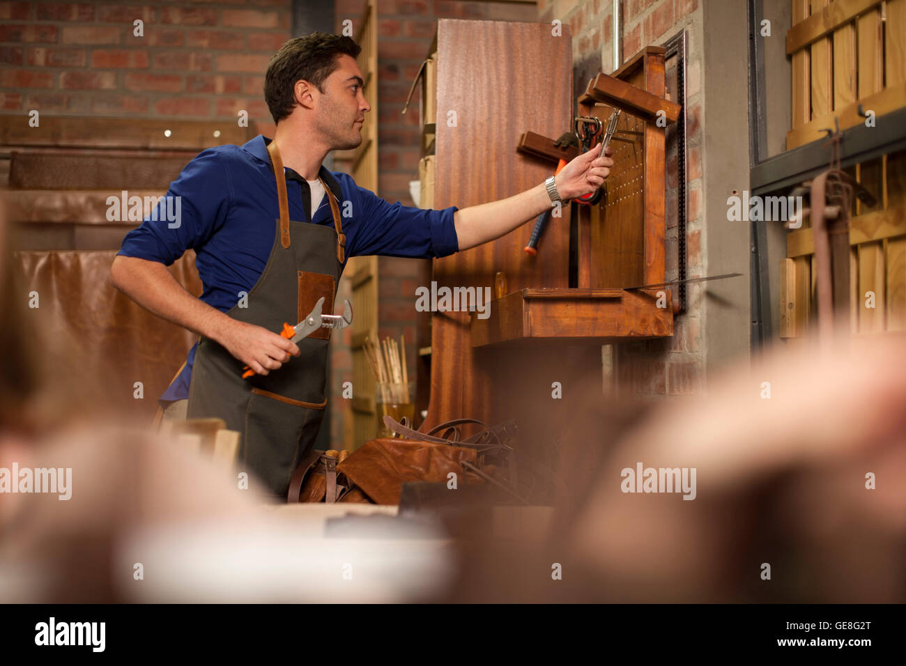 Man hanging up tools in workshop Stock Photo - Alamy