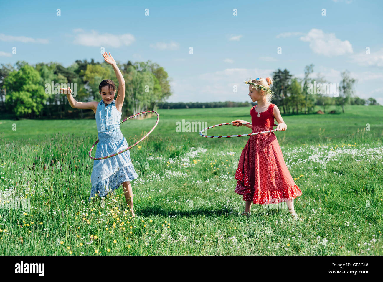 Two girls with hula hoops in meadow Stock Photo - Alamy