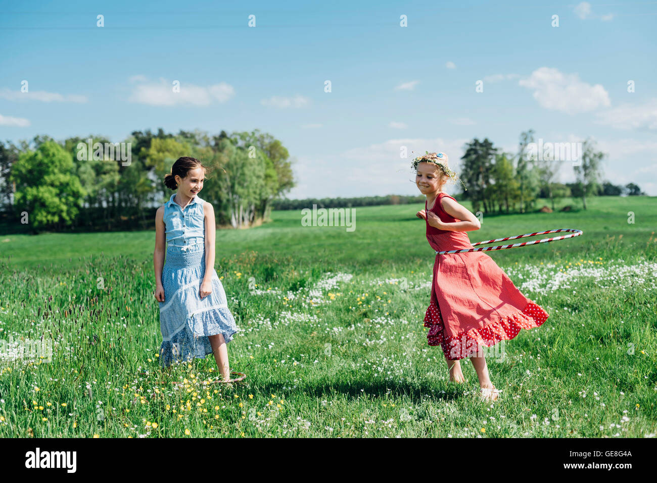 Two girls with hula hoop in meadow Stock Photo - Alamy