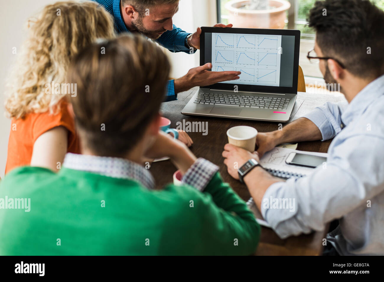 Young professionals analysing line graphs on laptop monitor Stock Photo ...