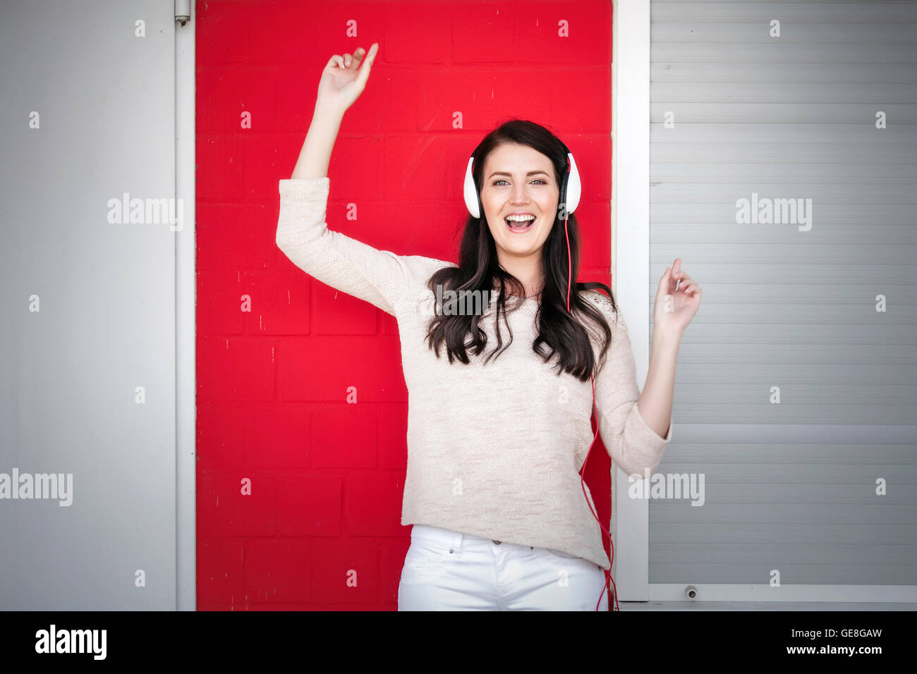 Portrait of singing and dancing woman hearing music with headphones ...