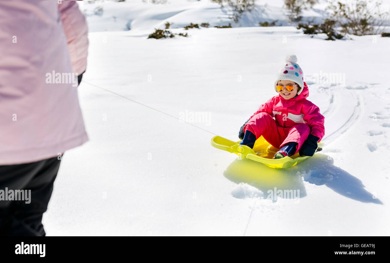 Girl sitting on sledge, mother pulling Stock Photo - Alamy