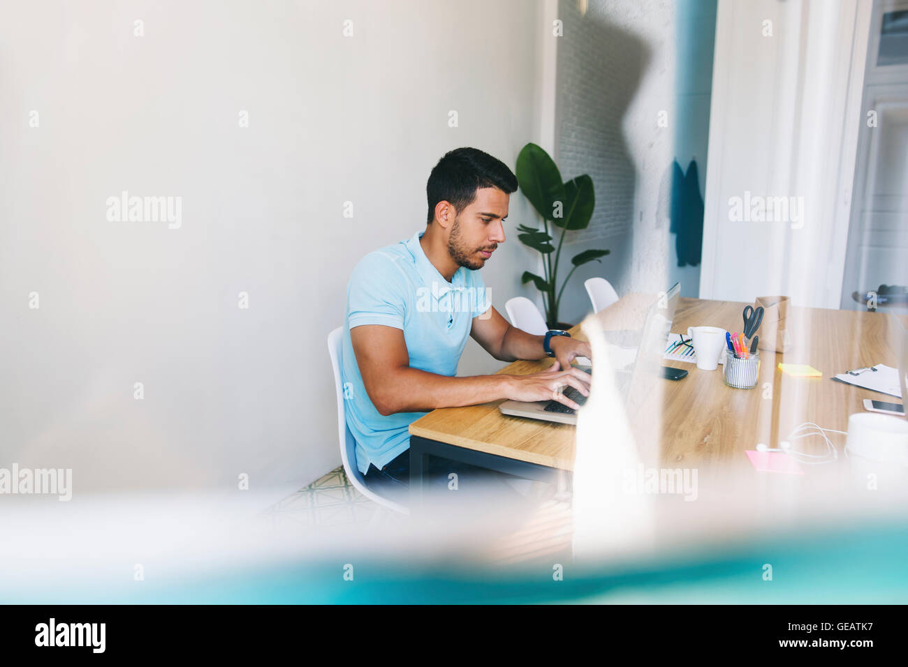 Young man working in office, using laptop Stock Photo - Alamy