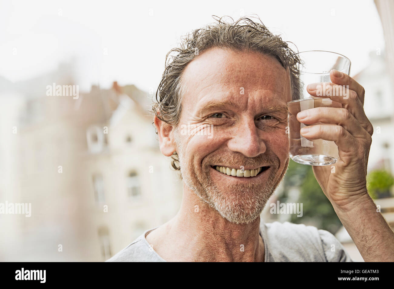 Portrait of smiling man toasting with water glass Stock Photo - Alamy