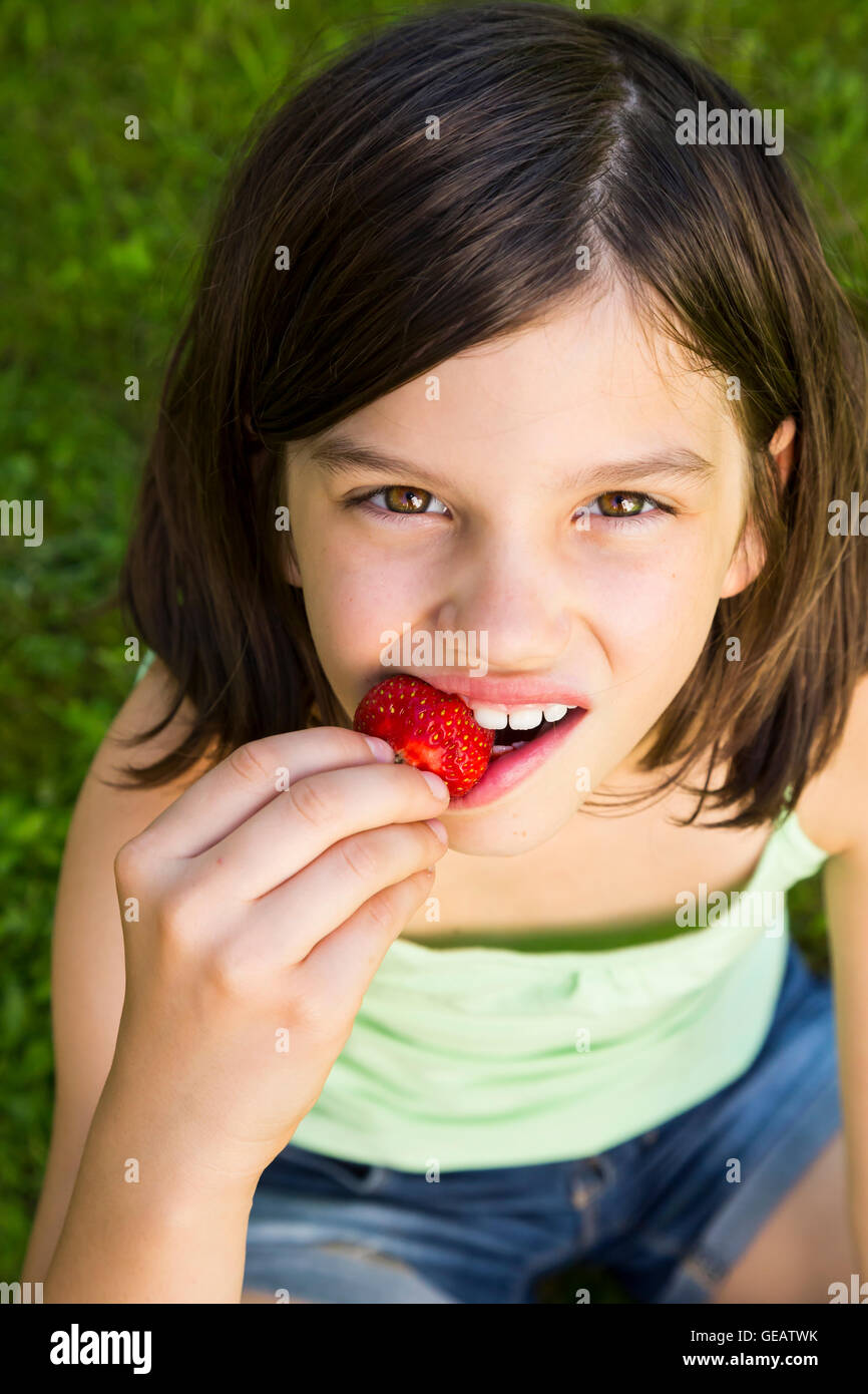 Portrait of girl eating strawberry Stock Photo - Alamy