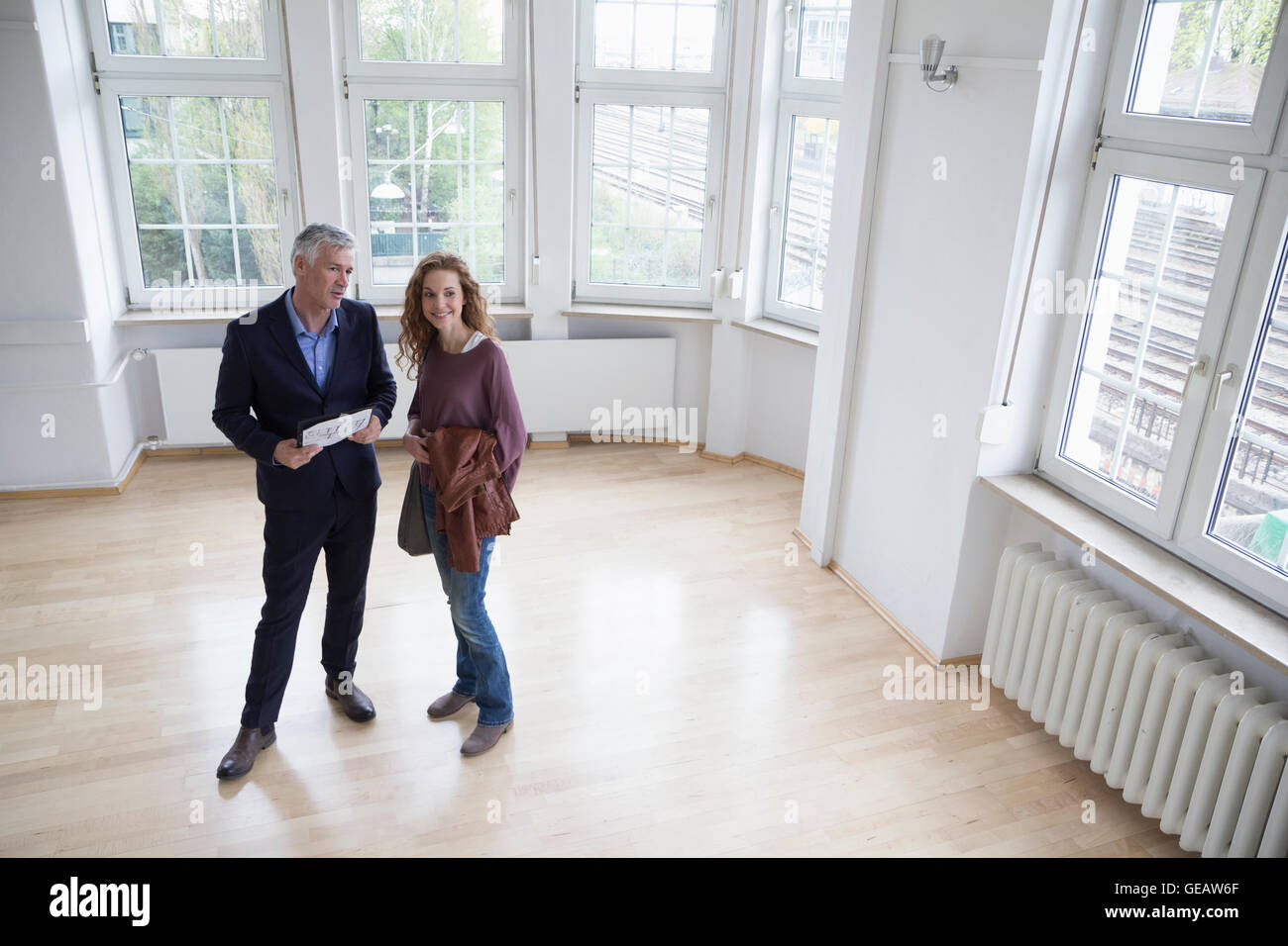 Real estate agent talking to client in empty apartment Stock Photo - Alamy