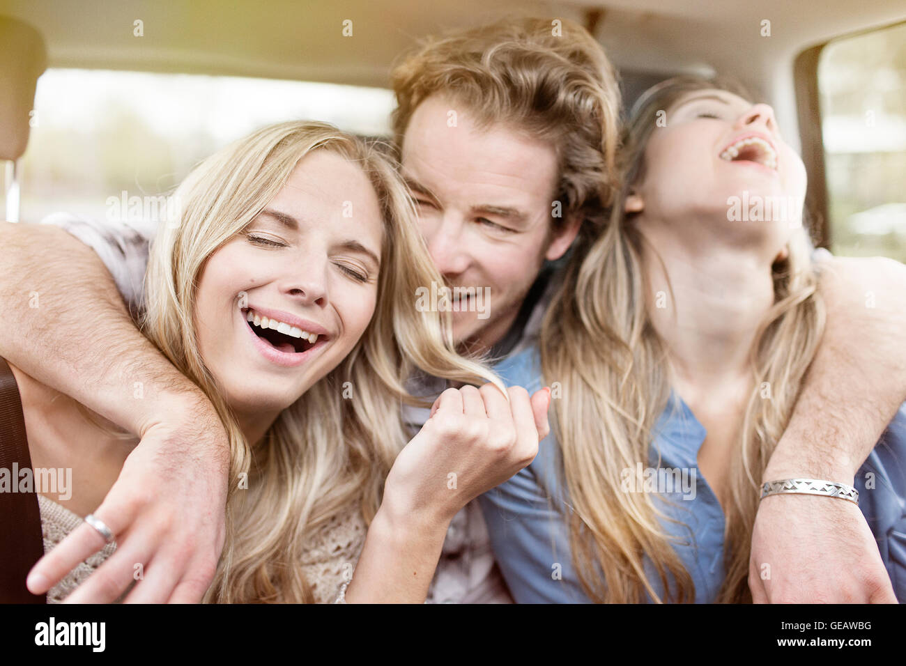 Three laughing friends sitting on backseat of car having fun Stock ...