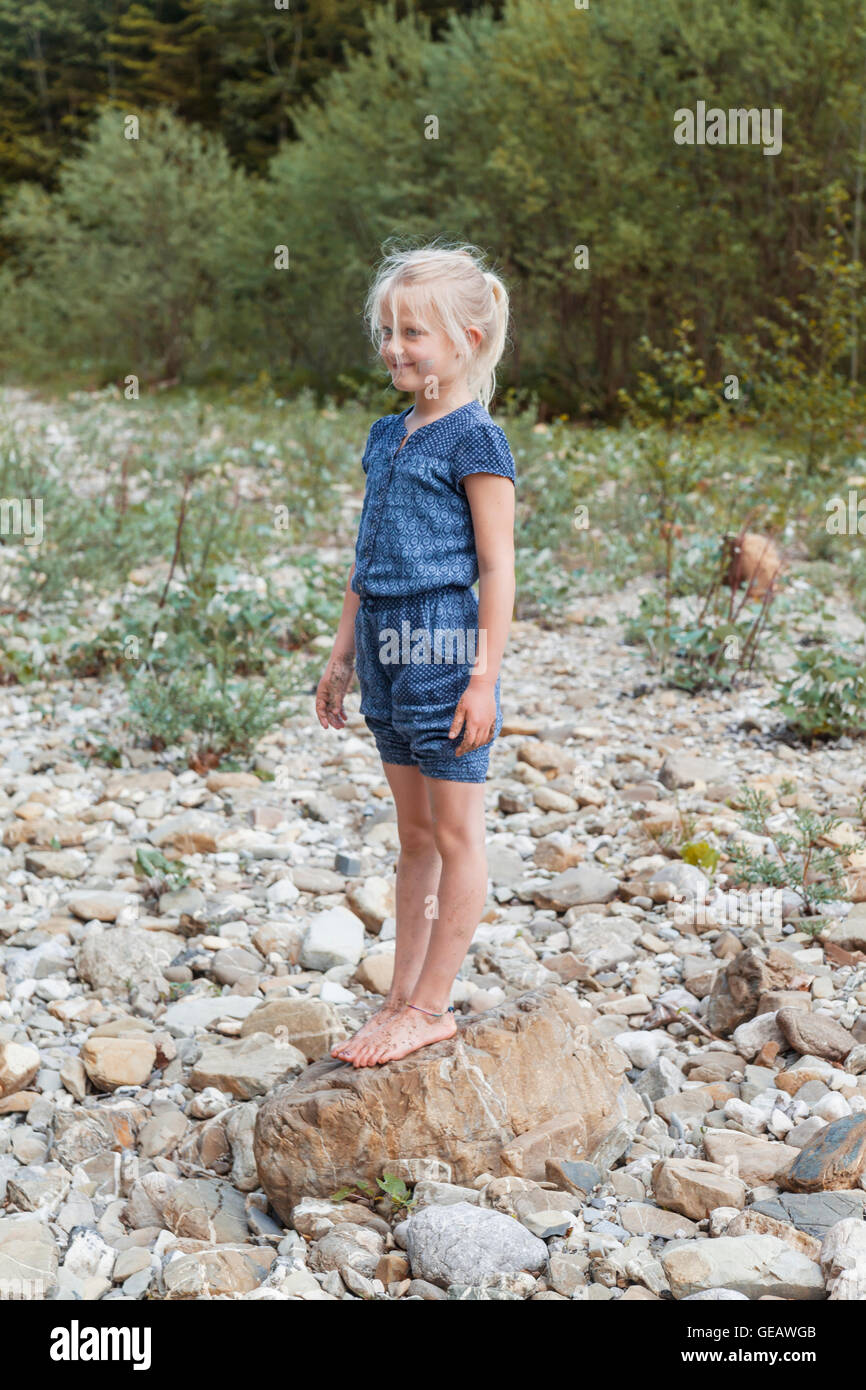 Smiling little girl standing on a rock in nature Stock Photo - Alamy