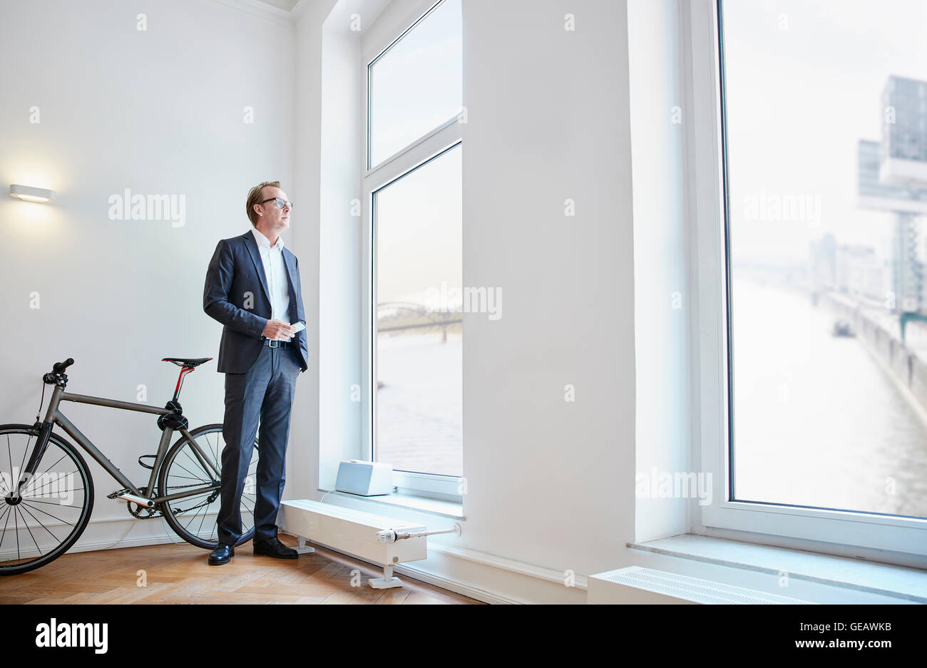 Businessman with smartphone looking through window Stock Photo - Alamy