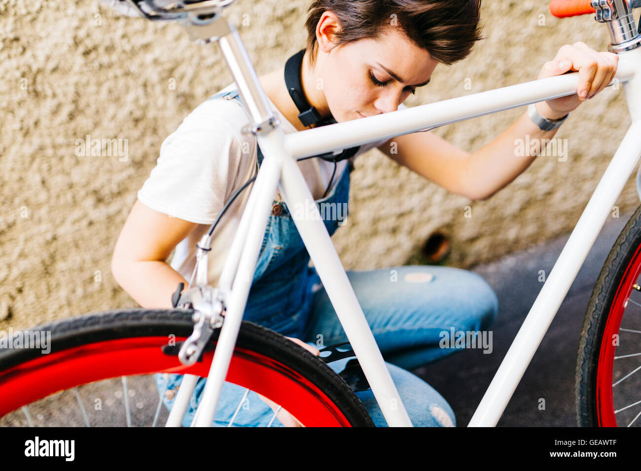 Young woman crouching at bicycle Stock Photo - Alamy