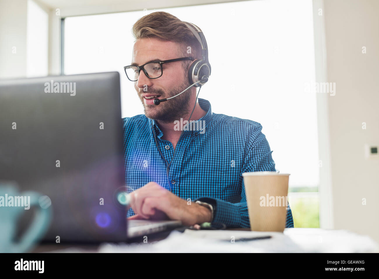 Man with headset and laptop in office Stock Photo - Alamy