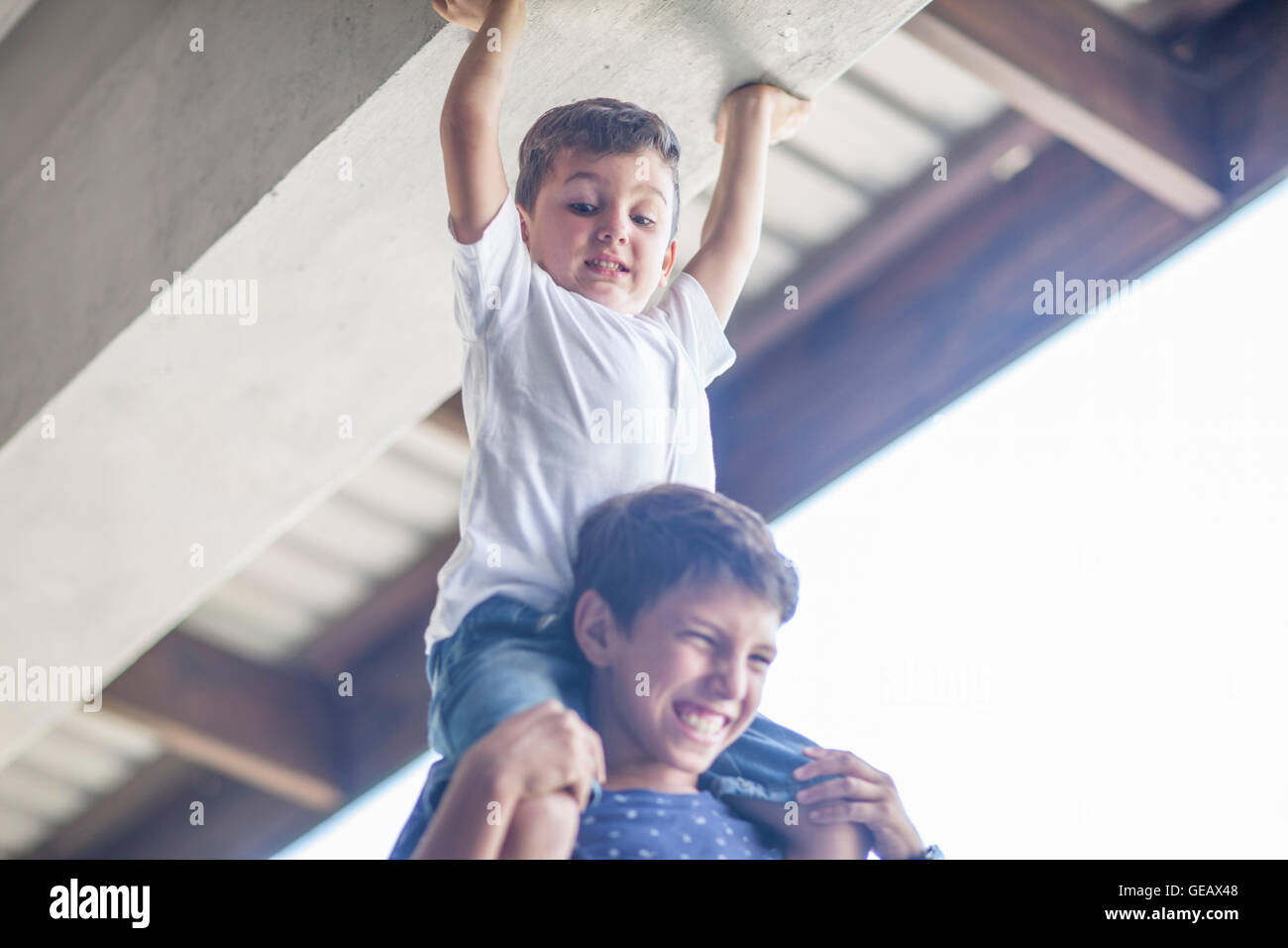 Little boy sitting on his brother's shoulders Stock Photo - Alamy