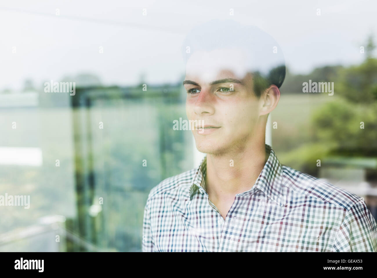 Young man looking out of window Stock Photo - Alamy