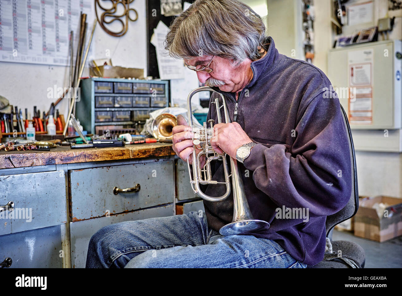 Instrument maker examining trumpet in workshop Stock Photo - Alamy