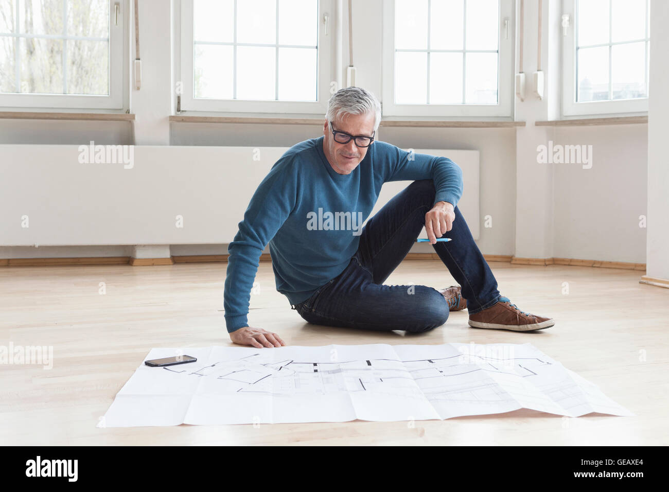 Man looking at construction plan in empty apartment Stock Photo - Alamy